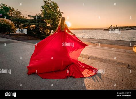 Sunrise Red Dress A Woman In A Long Red Dress Against The Backdrop Of