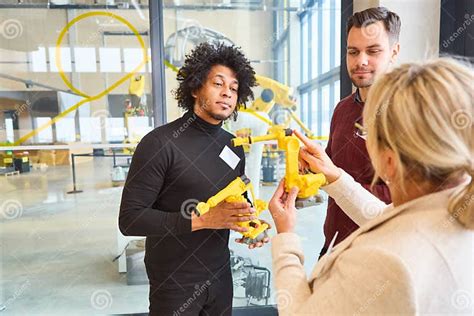 Engineers Discussing Robotics And Programming With A Focus On Gripper Arms In An Industrial