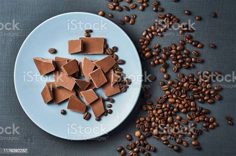 블루 서클 세라믹 플레이트에 쓴 또는 밀크 초콜릿의 많은 깨진 조각의 힙과 흩어져 튀긴 커피 콩 어두운 긁힌 콘크리트 테이블에 놓여있다 맨 위 보기 갈색에 대한 스톡 사진