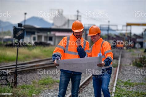건설 과정을 점검하는 엔지니어 철도 열차 테스트 및 무선 통신으로 철도 역에서 철도 작업을 점검합니다 직장에서 안전복과 안전 헬멧을 착용한 엔지니어 2명에 대한 스톡 사진