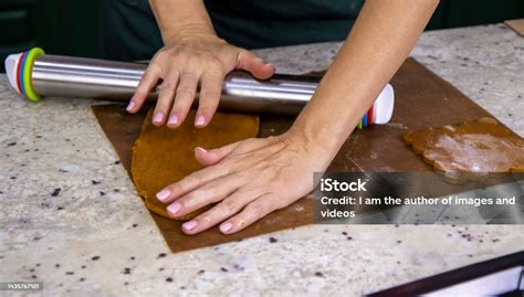 생강 쿠키를 만들기 위해 현대적인 금속 롤링핀으로 반죽을 굴리는 페이스트리 셰프의 여성 손의 모습 향기로운 디저트를 요리하고