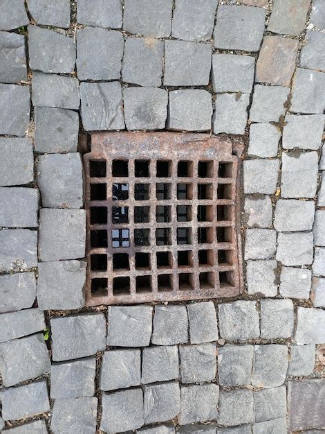 Premium Photo A Sewer Drain With A Rusty Iron Grate On A Stone