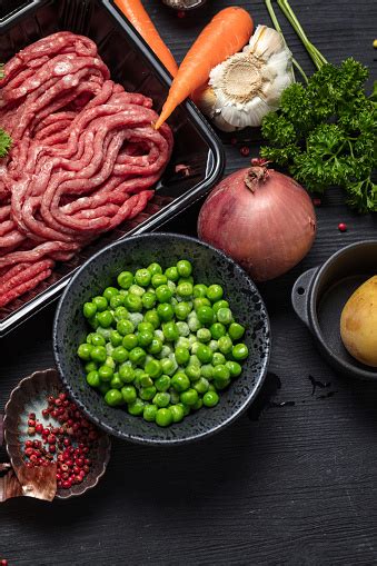 양치기의 파이 녹색 완두콩 당근 양파와 검은 배경 평면도에 조미료에 대 한 성분으로 둘러싸인 컨테이너에 원시 다진된 고기 수직 성분 0명에 대한 스톡 사진 및 기타 이미지