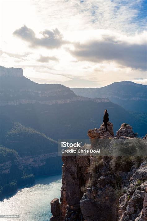 바위 절벽에 서서 반짝이는 호수를 배경으로 숨막히는 산 풍경을 감상하는 모험심 강한 여성 자유 탐험 자연의 아름다움에 대한 개념 Castillo De Chirel 발렌시아