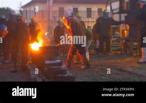 Workers Casting Hot Liquid Metal Together At Dusk Casting Orange Iron