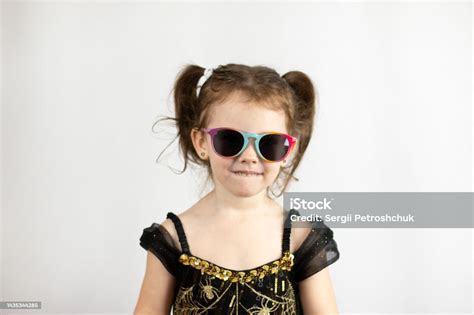 두 개의 포니 테일과 검은 색과 금색 드레스를 입은 어린 장난기 많은 소녀 선글라스를 쓴 어린이의 흰색 배경에 스튜디오 사진 2 3 살에 대한 스톡 사진 및 기타 이미지