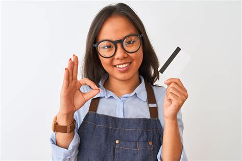 고립된 흰색 배경 위에 신용 카드를 들고 안경을 쓰고 있는 중국 상점 주인 여성은 손가락으로 확인 사인을하고 우수한 기호 개념에 대한 스톡 사진 및 기타 이미지 Istock