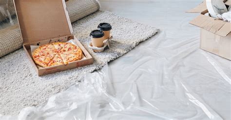 포장된 상자와 기타 물건으로 둘러싸인 소파 옆 바닥에 식욕을 돋우는 피자와 커피 두 잔이 담긴 상자를 엽니다 사진 Unsplash의 실내 이미지