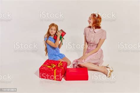아름다운 여자와 어린 소녀의 초상화 회색 배경 위에 격리된 귀 근처에서 선물 상자를 흔드는 아이 겨울 방학 1950 1959 년에 대한 스톡 사진 및 기타 이미지 Istock