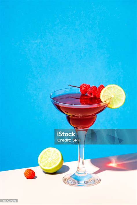 화이트 럼 라임 주스 시럽 석류 라즈베리 여름 파란색 밝은 배경 단단한 빛과 그림자를 곁들인 La Bomba Daiquiri 알코올 칵테일 음료 사진 이미지에 대한 스톡