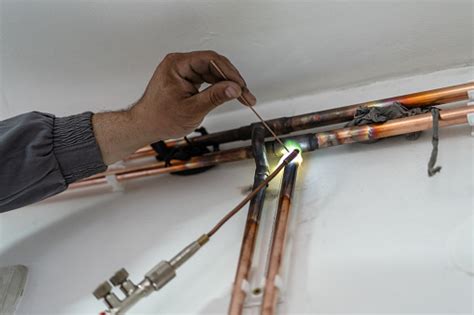 집 건물이나 아파트 벽에 가스 토치 또는 블로토치를 사용하여 용접 중앙 난방 구리 파이프와 알 수없는 산업 노동자 배관공 작업