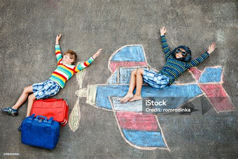 두 명의 어린 아이 아스팔트에 화려한 분필로 비행기 그림 그리기와 함께 즐거운 시간을 보내는 어린이 소년 분필로 그림을 그리는 친구들 휴가와 여행 컨셉 공항 계류장에 대한