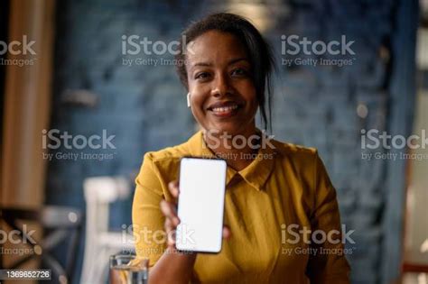 카페에 앉아있는 동안 스마트 폰을 보여주는 아름다운 젊은 아프리카 계 미국인 여성 가리키기에 대한 스톡 사진 및 기타 이미지 가리키기 휴대전화 보여주기 Istock