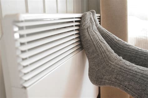전기 히터 위로 따뜻해지는 니트 양말의 다리 겨울 추위에 얼어 붙은 따뜻한 모직 양말을 착용 한 냉동 여성 집에서 시간을 보내는 불편 함 현대 라디에이터에서 발을 따뜻하게