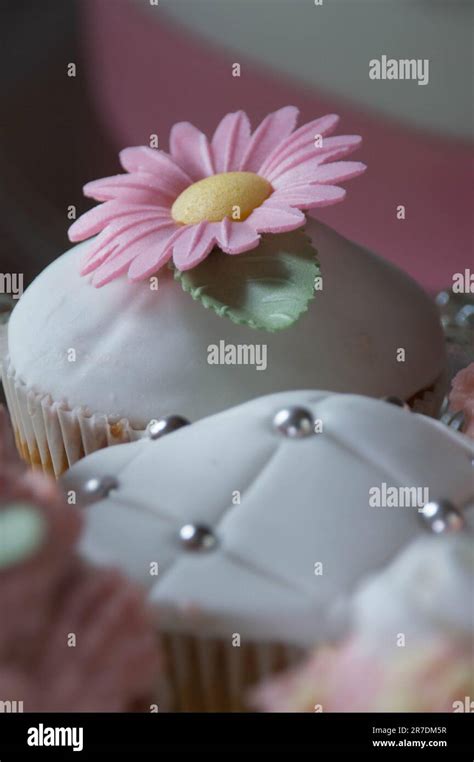 A Colorful Assortment Of Cupcakes With White Frosting And Edible Flower Decorations In An