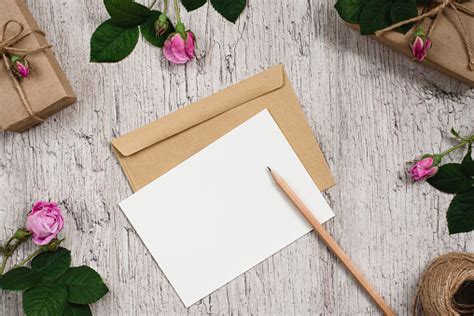 회색 테이블에 크래프트 페이퍼와 분홍색 장미 꽃으로 싸여 선물 상자 텍스트에 대한 용지의 빈 시트입니다 맨 위 보기입니다 플랫 레이 공간을 복사합니다 선물에 대한 스톡 사진