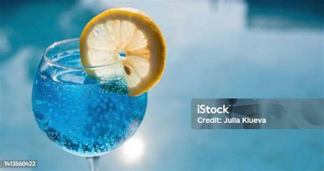 수영장 배경에 맛있는 파란색 칵테일 블루 라군과 노란색 레몬 한 잔 알콜 칵테일 육즙이 많은 과일 블루와 Curacao 리큐어 아이스 큐브 및 레몬 조각 0명에 대한 스톡