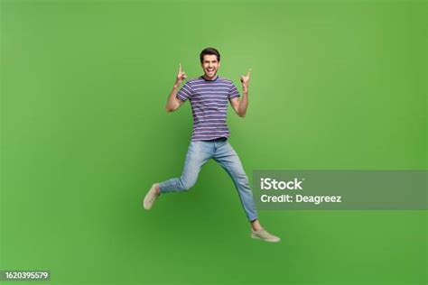 미친 멋진 남자의 전체 길이 사진은 줄무늬 티셔츠를 입고 높은 곳에서 단단한 바위 표지판을 보여 주며 고립 된 녹색 배경을 보여줍니다 25 29세에 대한 스톡 사진 및 기타