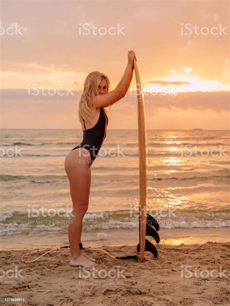 따뜻한 일몰 이나 일출에 서핑 보드와 모래 해변에 서퍼 소녀 해변에서 매력적인 서퍼 여성 25 29세에 대한 스톡 사진 및 기타 이미지 25 29세 가냘픈 관능