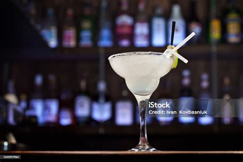 바 카운터에서 화이트 칵테일 마티니 진 데킬라 라임과 함께 술을 마시는 병을 배경으로 마십니다 나무 판에 술이 있는 유리 자외선