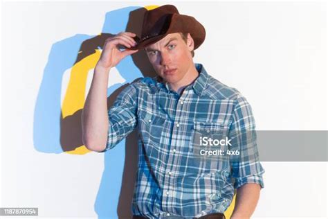 허리 까지 1 인 성인 잘 생긴 사람 금발 머리 짧은 머리 백인 남성 젊은 남성 앞에서 멀티 컬러 배경 컬러 배경 착용 목재 잭 셔츠 카우보이 모자 모자 청바지 주머니에