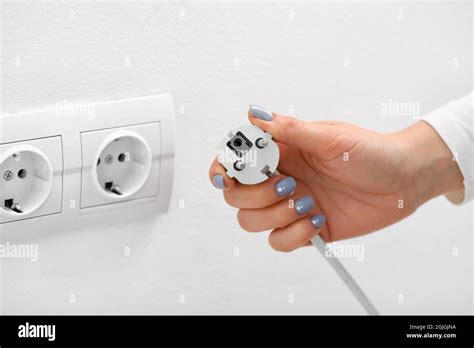 Woman Putting Plug Into Socket In Room Stock Photo Alamy
