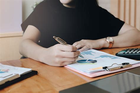 여성 관리자는 자신의 아이디어를 넣고 직장에 사업 계획을 작성하고 펜과 서류를 들고 문서에 메모를 하고 사무실에 있는 테이블에 메모를 작성합니다 개념에 대한 스톡 사진 및