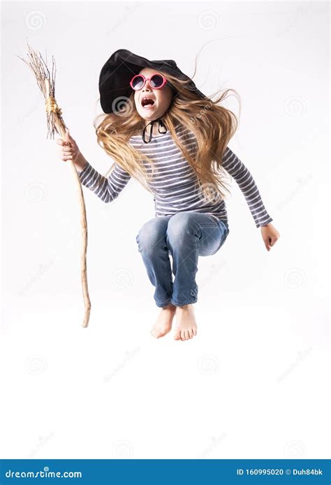 Девушка в колдуне прыгает на матрас с метлой Стоковое Фото