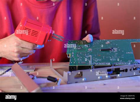 Soldering The Motherboard With A Transformer Soldering Iron By A Person In A Red Sweatshirt