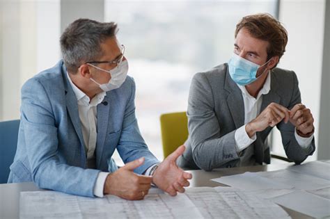 회의에서 재정을 논의하는 얼굴 마스크를 착용한 두 명의 사업가 25 29세에 대한 스톡 사진 및 기타 이미지 25 29세 2명 50 54세 Istock