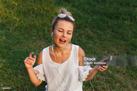 헤드폰과 기호와 전화에 음악을 듣고 행복한 소녀 스마트 폰용 앱의 오디오 젊은 여성이 춤을 추고 손에 스마트 폰으로 야외에서 즐거운 시간을 보세요 Mp3 플레이어에 대한