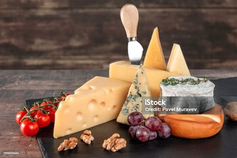 검은 슬레이트 보드와 소박한 나무 배경에 호두 토마토와 포도와 다른 유형치즈 여전히 생활 블루 치즈 도르블루 훈제 치즈 브리 마스담 체다 파르메산 치즈보드에 대한 스톡 사진