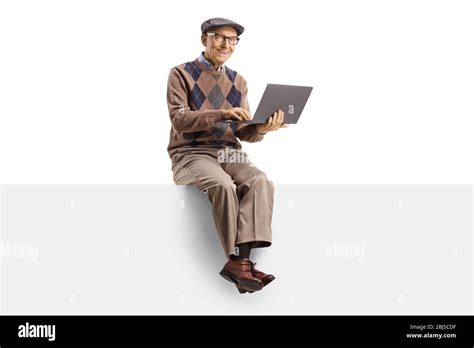 Elderly Man Sitting On A Blank Panel And Using A Laptop Computer Isolated On White Background