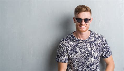 서 치아를 보여주는 자신감 미소로 웃 고 행복 한 얼굴로 선글라스를 입고 회색 그런 지 벽에 빨강 머리 젊은 남자 건강한 생활방식에 대한 스톡 사진 및 기타 이미지 Istock