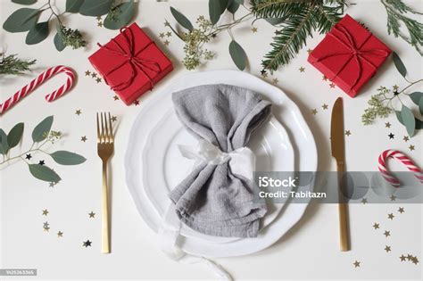 크리스마스 꽃 테이블 설정 전나무 베리 유칼립투스 나무 가지 빨간 선물 상자 사탕 지팡이 및 흰색 테이블 배경에 고립 된 황금