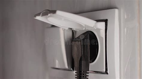 The Man S Hand Opens The Protective Cover In The Socket And Inserts A Black Electrical Plug