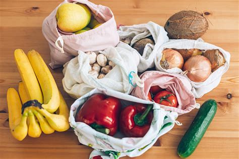 제로 폐기물 쇼핑 개념입니다 나무 테이블에 에코 코 튼 가방에 신선한 야채 후추 사탕 무 토마토 오이 바나나와 양파 코코넛 버섯 사과를 재사용 가능한 가방에 반 플라스틱 0