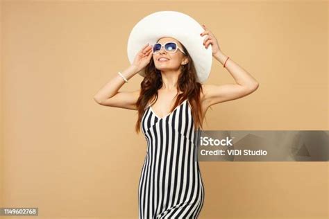 검은 색과 흰색 줄무늬 드레스 모자와 선글라스에 부드러운 젊은 여자는 파스텔 베이지색 벽 배경에 고립 된 눈을 폐쇄 유지 사람들은 진심으로 감정 라이프 스타일 개념입니다