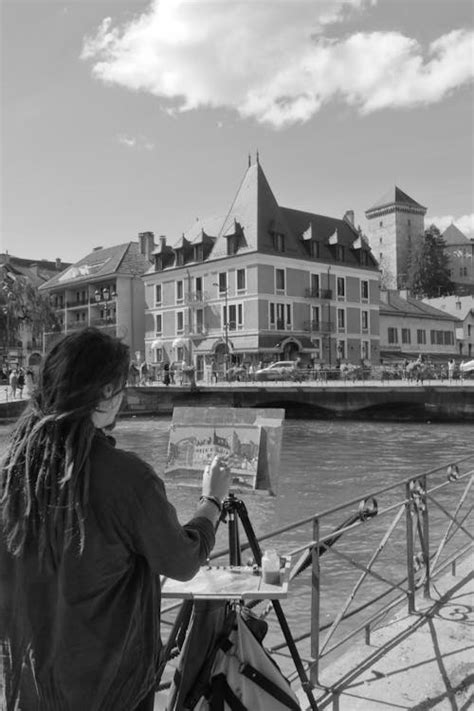 역사적 건물이 있는 강변에서 그림을 그리는 예술가 · 무료 스톡 사진