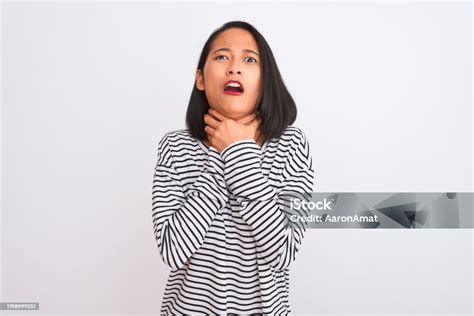 줄무늬 티셔츠를 입은 젊은 중국 여성이 고립된 흰색 배경 위에 서서 고통스러운 목졸림 때문에 외치고 질식합니다 건강 문제 질식 과 자살 개념 T 셔츠에 대한 스톡 사진 및