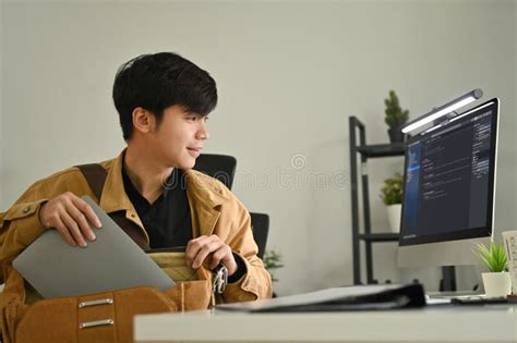 Asian Male Programmer Sitting Front Of Computers With Coded Data On Screen Putting His Stuff