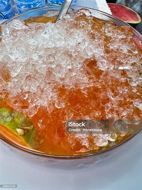 오렌지 주스 오렌지 감귤류 과일 조각 금속 서빙 국자 얼음 조각 및 으깬 얼음 슬러시의 오렌지 음료로 응축으로 덮인 유리 용기의 전체 프레임 이미지 높은 뷰 전경에 초점 0