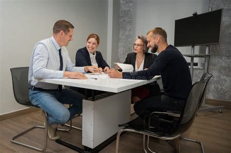 Four Colleagues Are Discussing Blueprints In A Conference Room In An Office Brainstorming Of