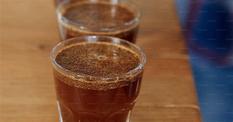 유리 컵에 갓 내린 커피 냄새를 맡고 숟가락을 사용하여 바로스타에 대한 커피 커핑 테스트에서 커피 맛과 풍미를 검사하는 남자의