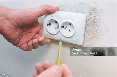 남자는 그의 손에 흰색 플라스틱 소켓 드라이버를 들고 있다 유지 보수 수리는 평면에서 혁신을 작동 합니다 실내 복원 전기 및