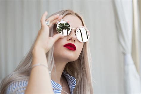 거리에서 카메라에 포즈를 취하는 긴 머리와 예쁜 금발 소녀의 초상화 그녀는 파란색 드레스와 안경을 착용 25 29세에 대한 스톡