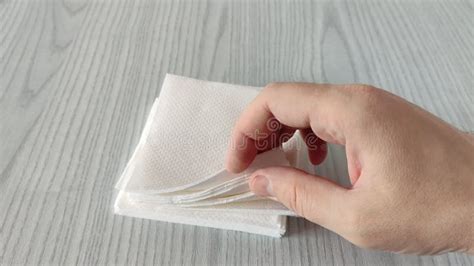 man sorting or selecting a napkin from a stack of white paper napkins