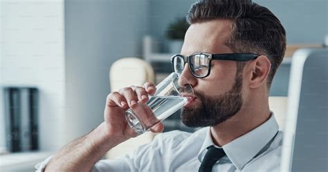 셔츠를 입고 넥타이를 맨 잘생긴 청년이 사무실에 앉아 물을 마신다 사진 Unsplash의 목마른 이미지