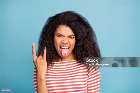 사진 예쁜 시원한 어두운 피부 아가씨 만들기 손가락 뿔 을 고집 혀 밖으로 입 기뻐 하는 바위 콘서트 착용 캐주얼 스트라이프