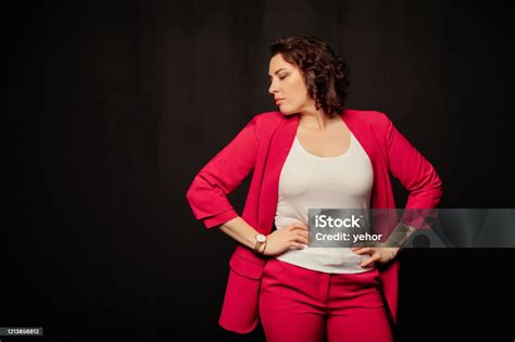 빨간 양복을 입은 한 여성이 허리띠에 손을 얹고 검은 색 배경으로 고개를 돌린다 여유 공간 검은 배경에 매력적인 사업가 복사 공간 갈색 머리에 대한 스톡 사진 및 기타